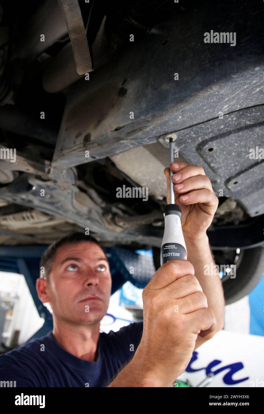 Worker using screwdriver in car repair shop Stock Photo - Alamy