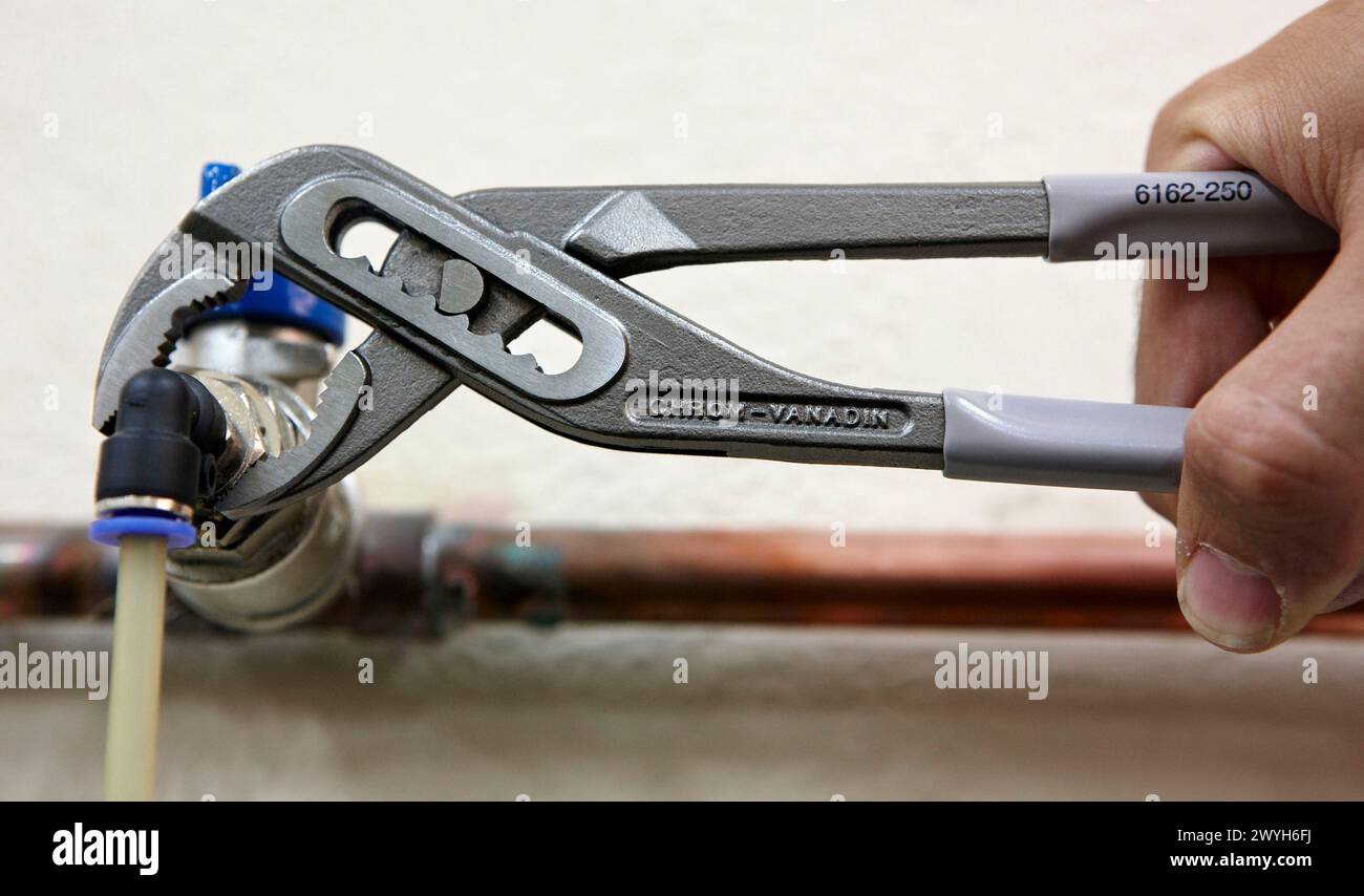 Worker using tongue-and-groove pliers Stock Photo - Alamy