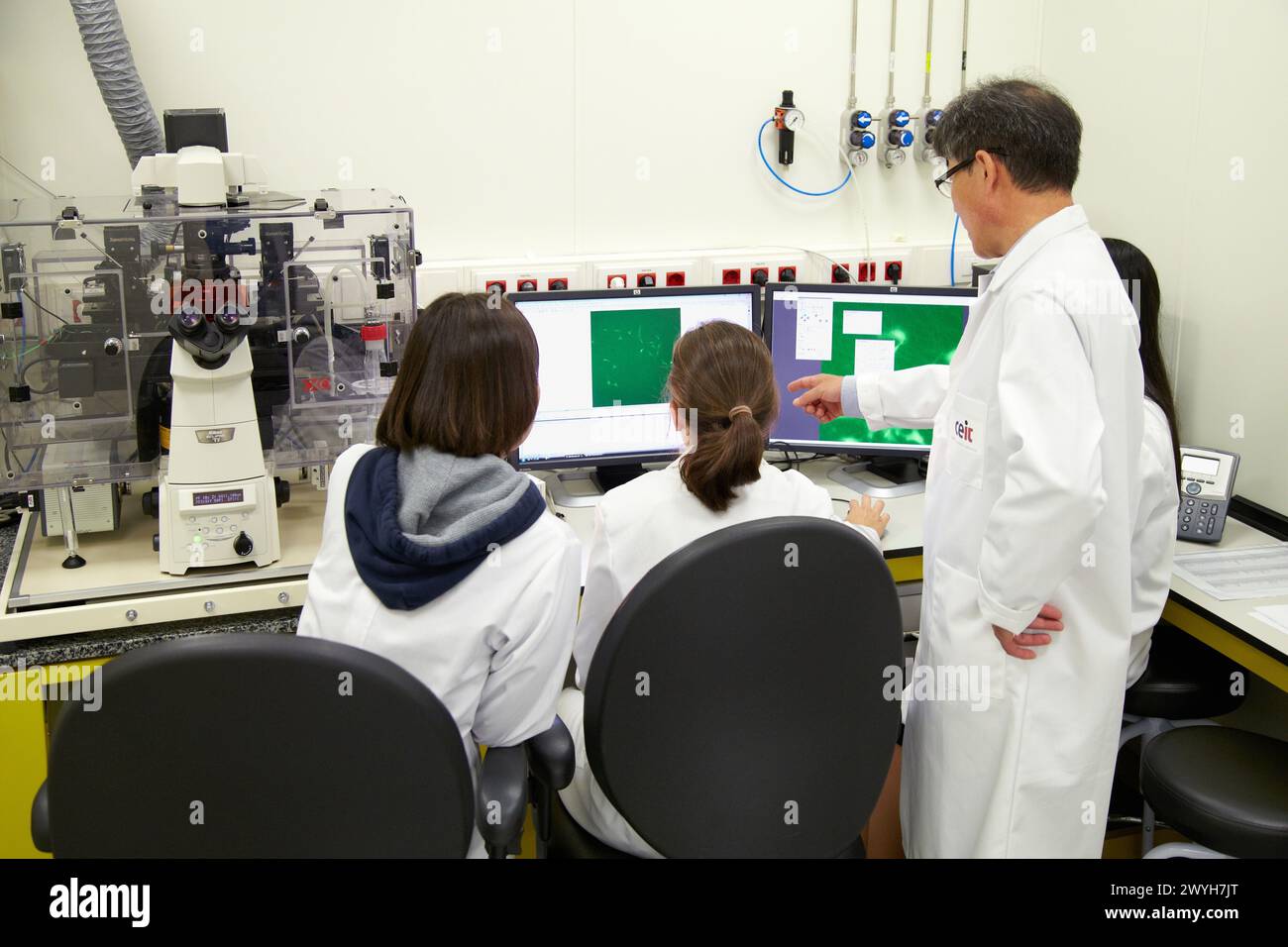 Teacher and students. Inverted optical microscope. With incubator ...
