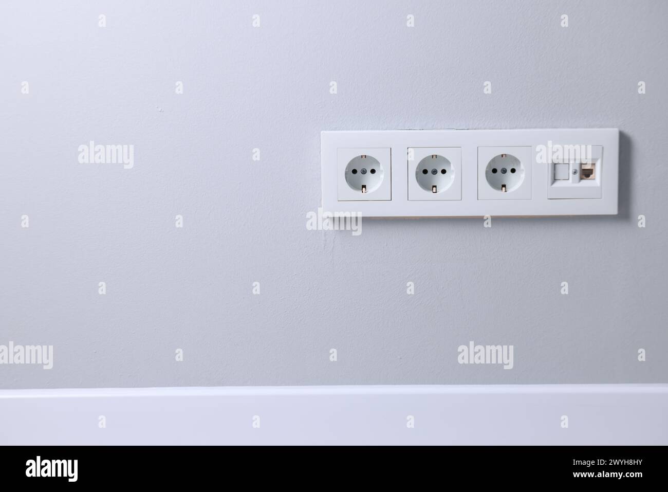 Electric power sockets on light grey wall indoors, space for text Stock ...