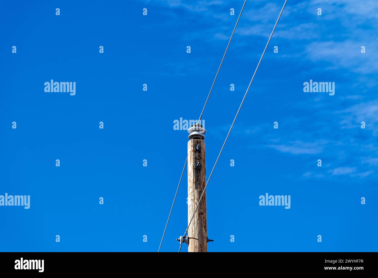 A utility pole that supports two cables with a clear blue sky Stock ...