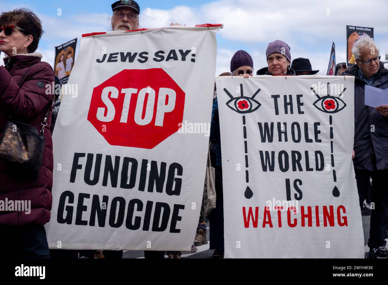 Protesters holding a banners that say "the Whole World is Watching" and ...