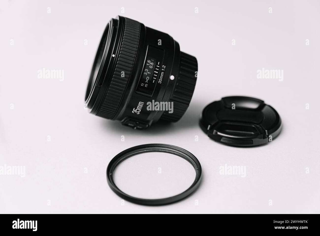 A professional 35mm camera lens accompanied by a lens filter and cap ...
