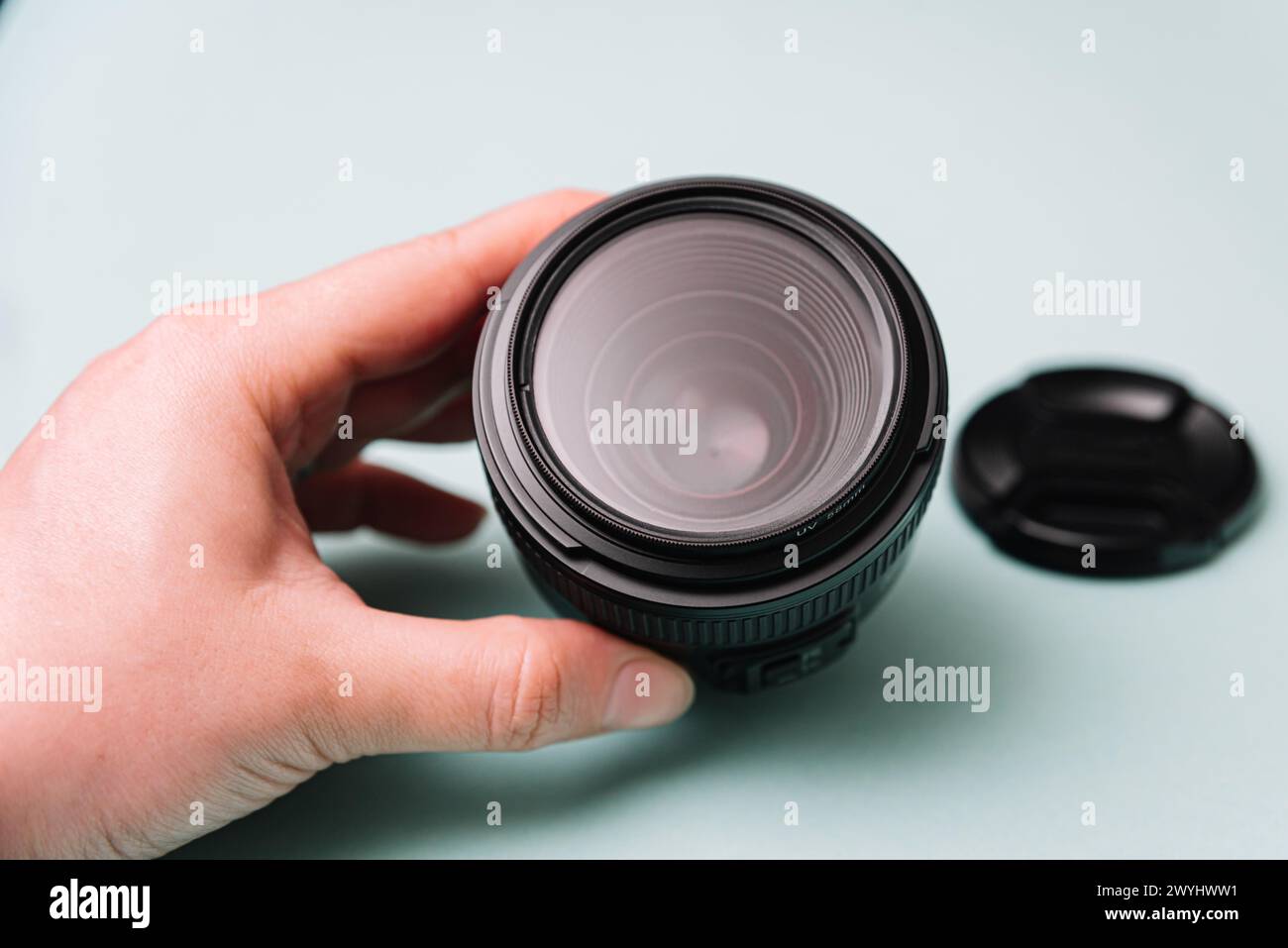 A photographer's hand holding a professional camera lens with the cap ...