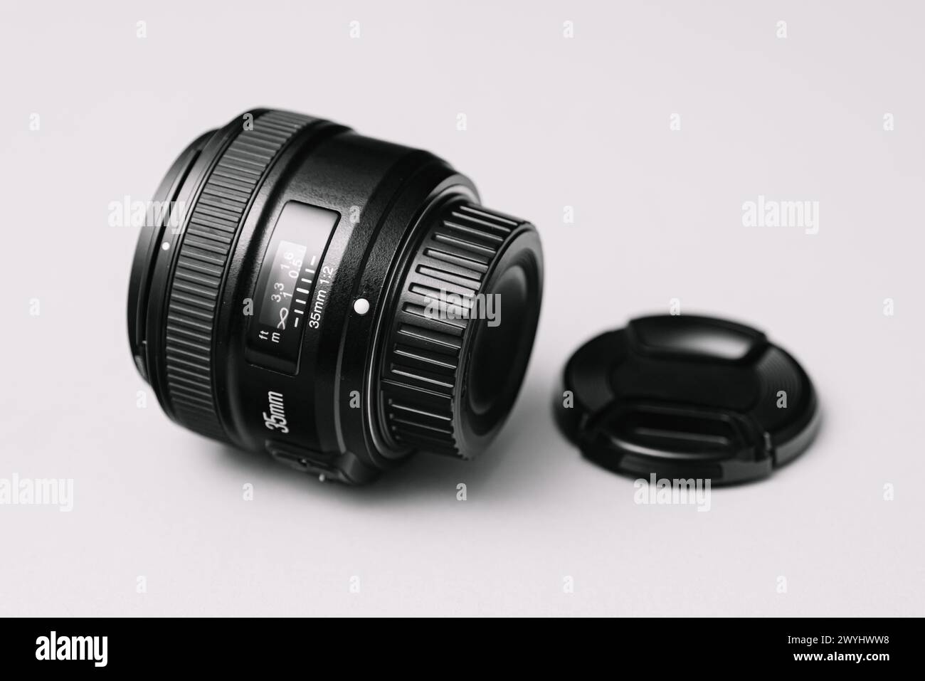 A black 35mm prime lens with distance and depth of field scale, next to ...