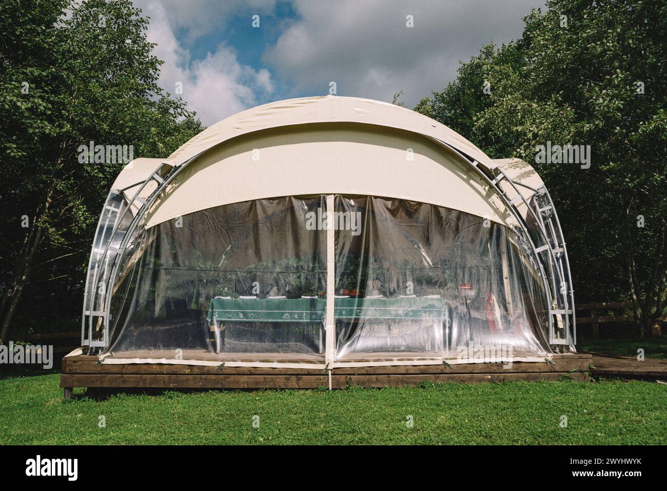 A transparent geodesic dome tent set up on a wooden platform in a ...