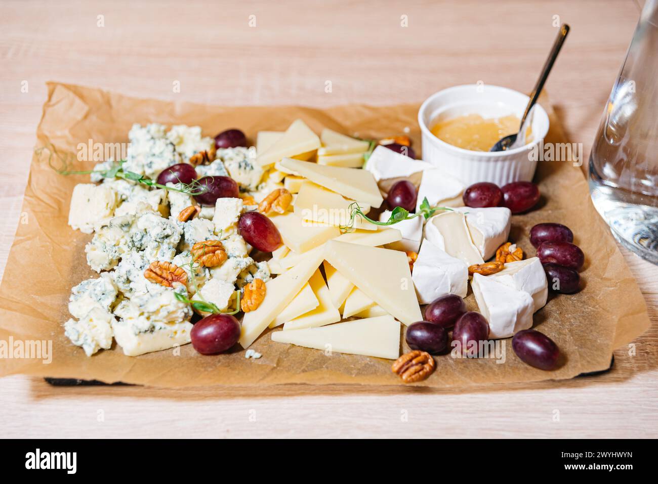 An assorted cheese board featuring blue cheese, brie, cheddar, grapes ...
