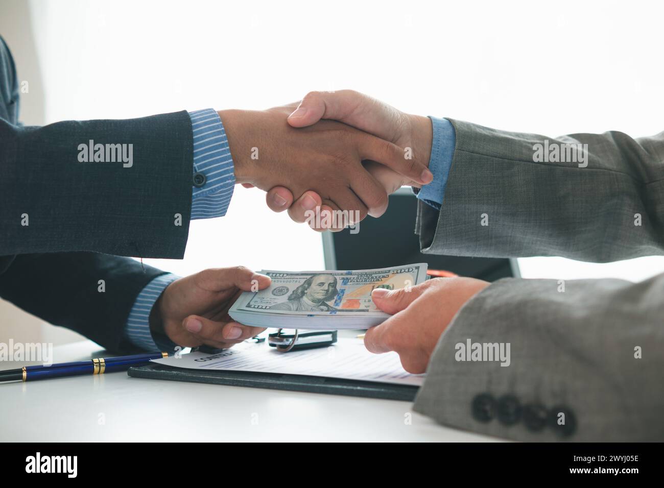 customer and car dealer shake hands after agreeing to sales contract ...