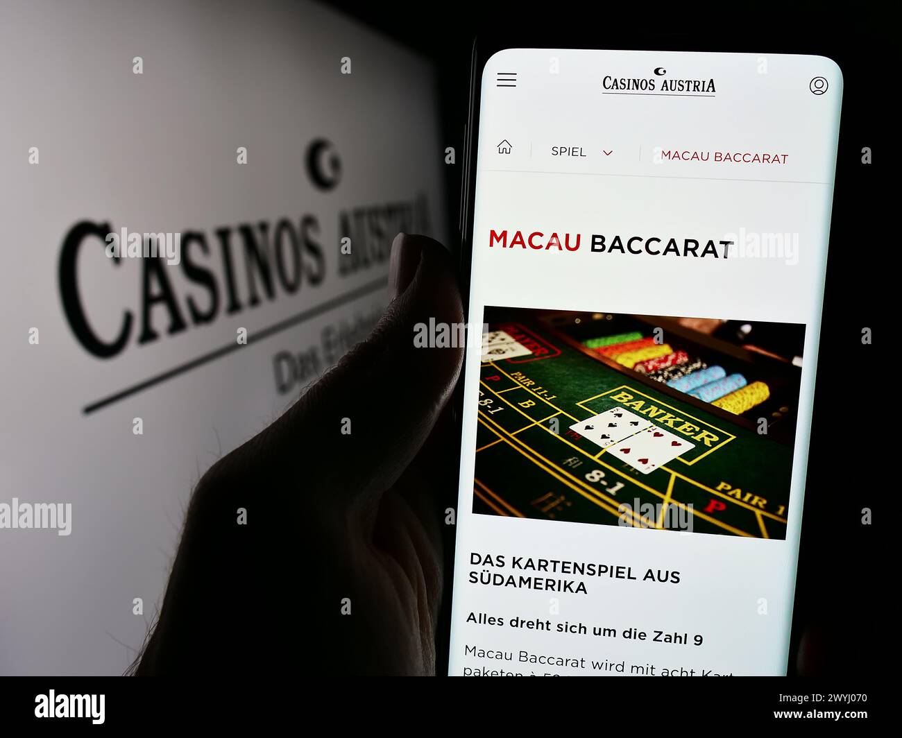 Person holding cellphone with webpage of Austrian gambling company ...