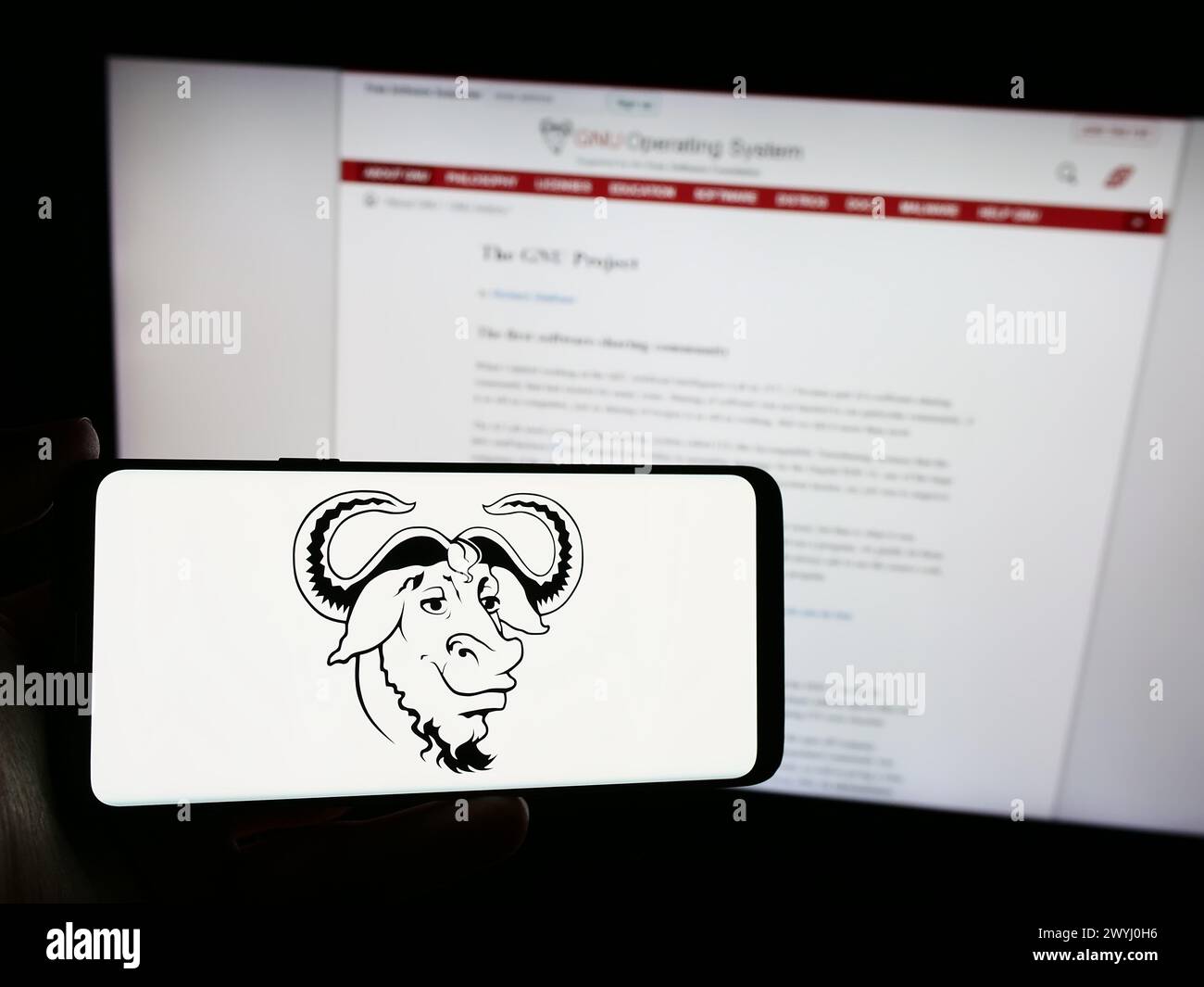Person holding smartphone with logo of software collaboration project GNU Project in front of ...