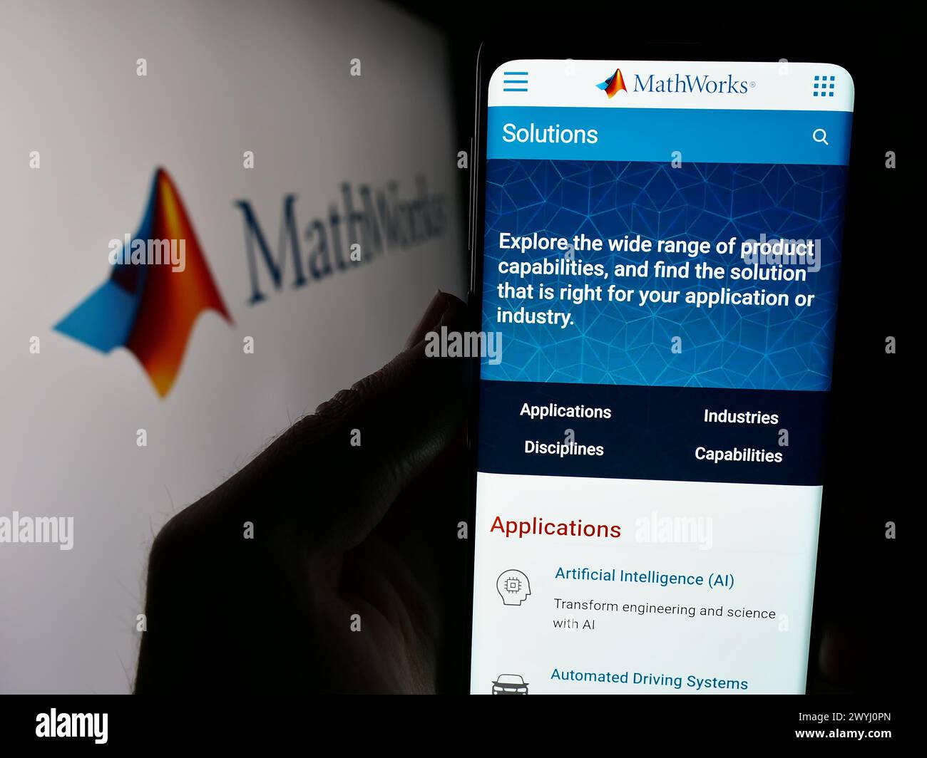 Person holding smartphone with webpage of US computing software company The MathWorks Inc. in ...