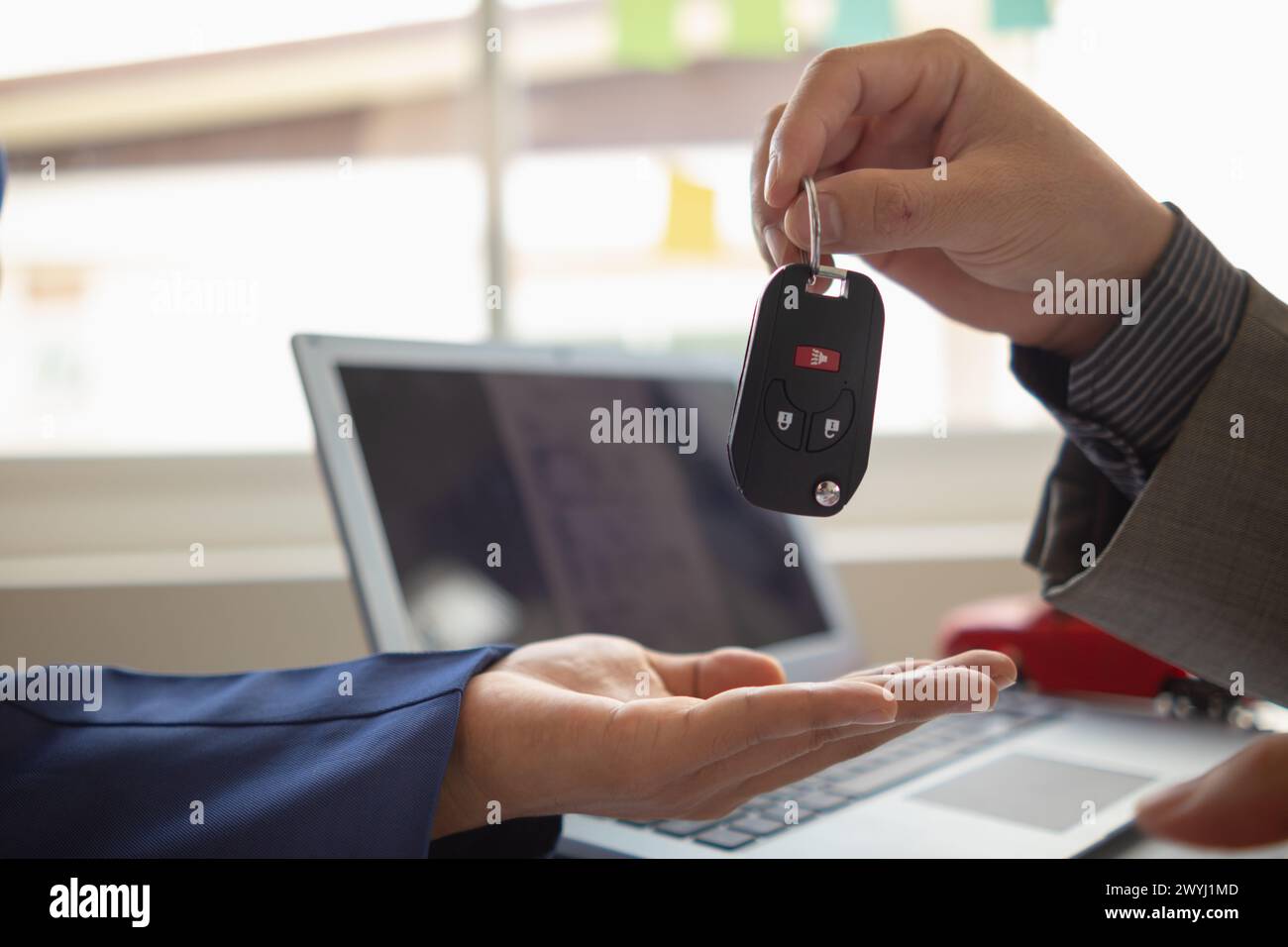 car dealer is handing over car keys to customer after sales contract ...