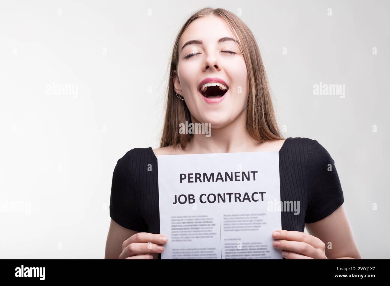Exuberant young woman celebrates holding a permanent job contract Stock ...