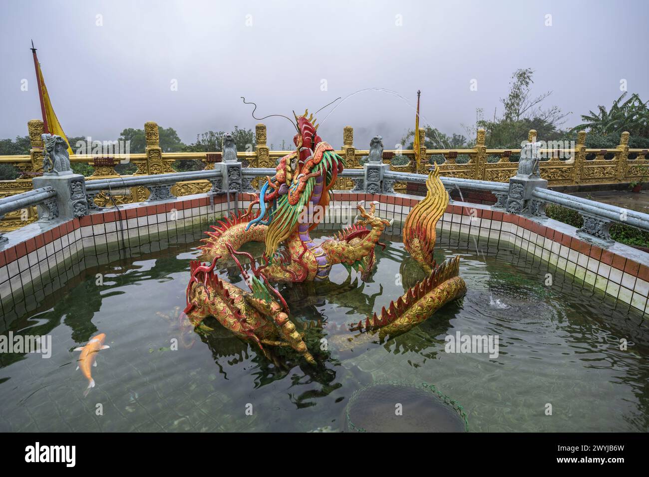 A colorful dragon statue emerges from a misty pond where there are ...