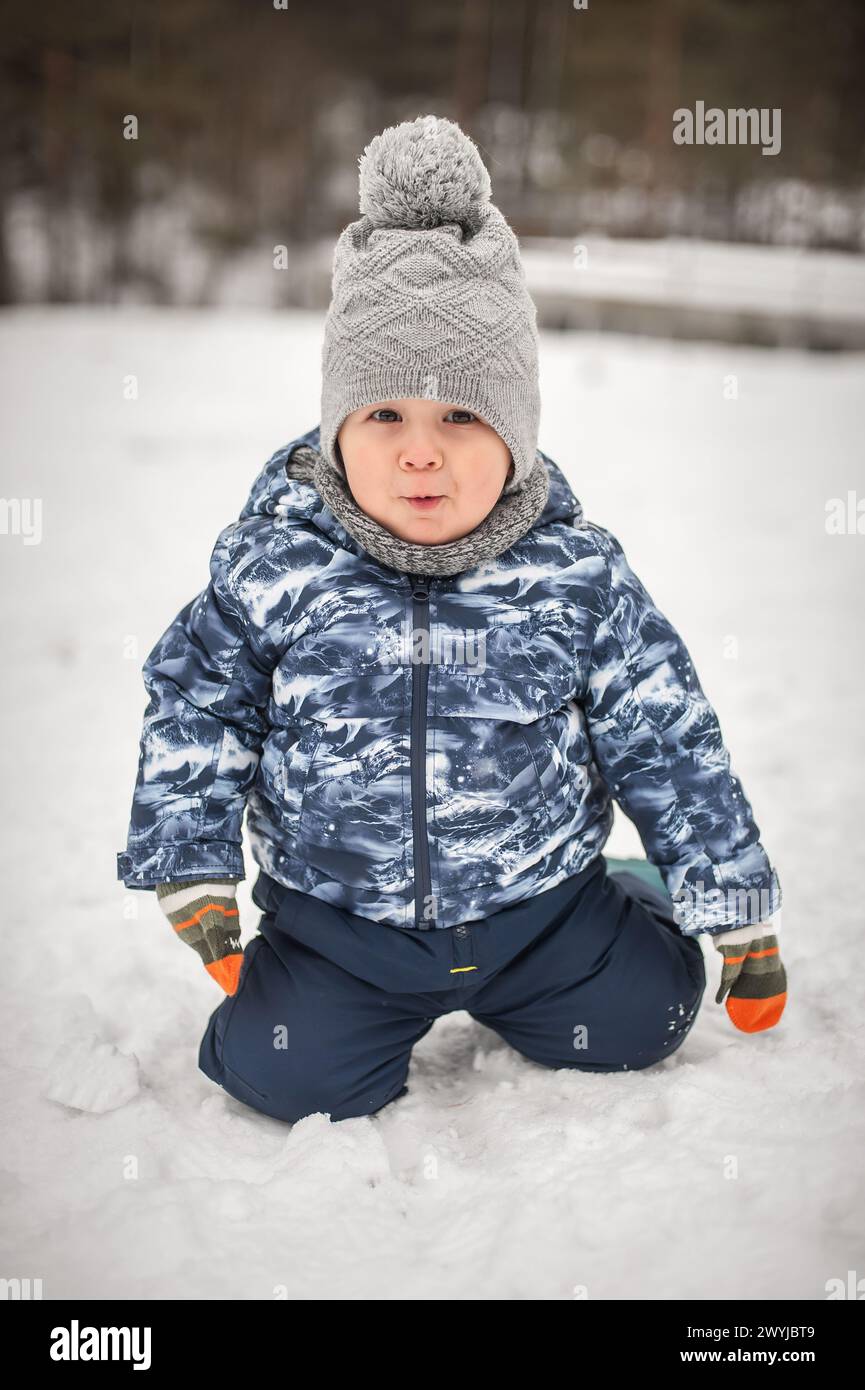 Adorable laughing toddler boy playing outside in snow on beauty winter ...