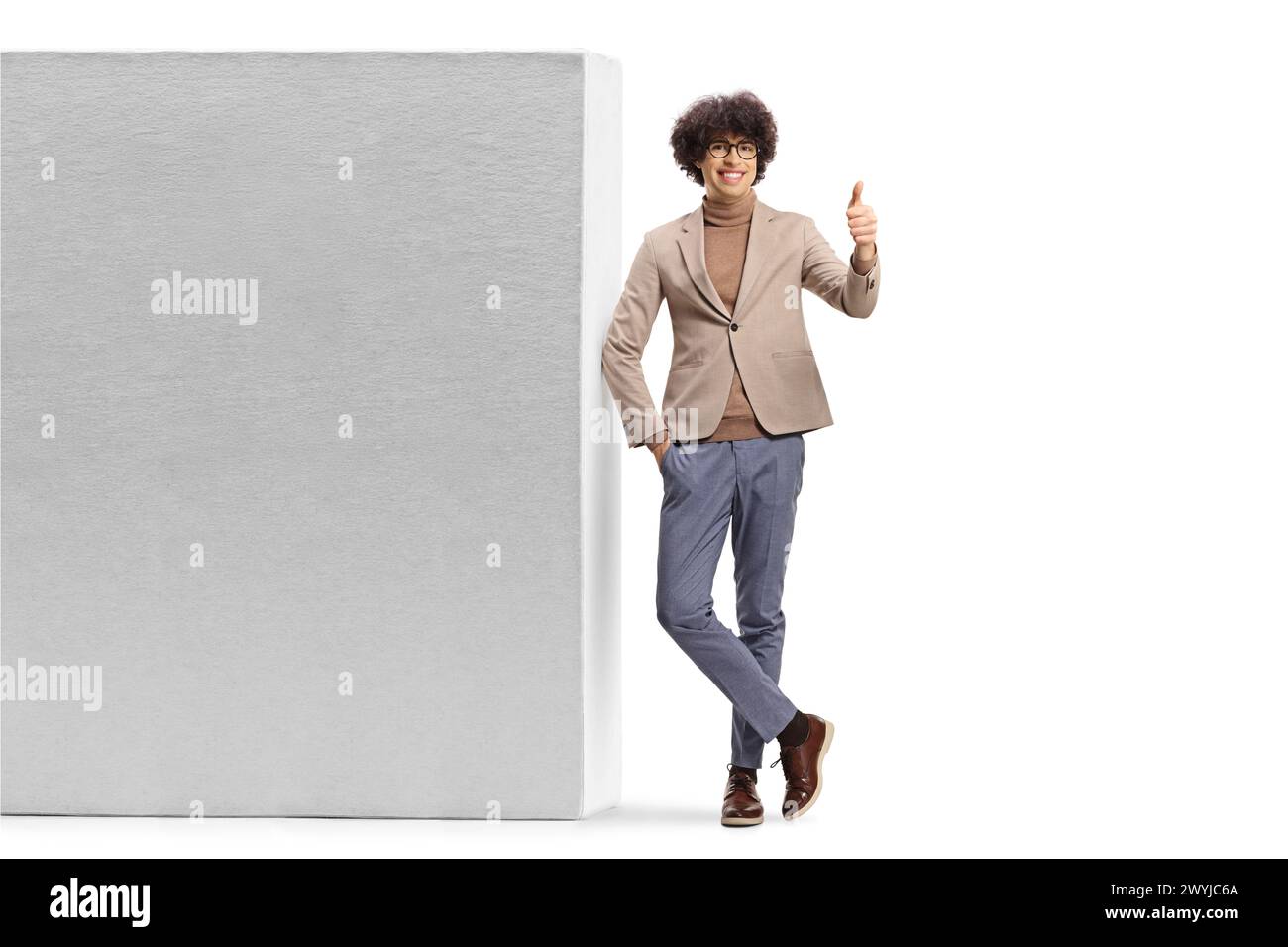 Tall young man leaning on a wall and gesturing thumbs up isolated on ...