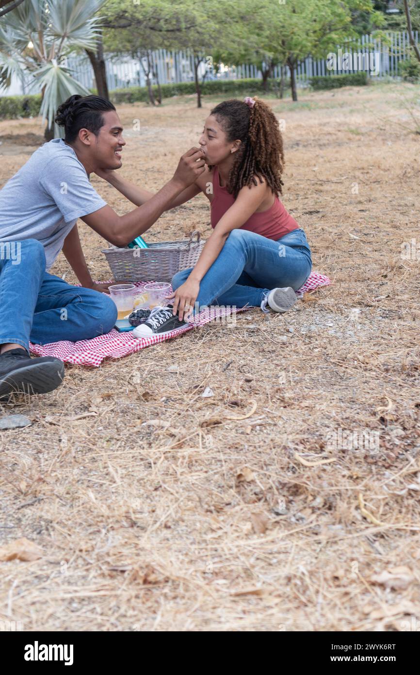Playful couple sharing food at a relaxed picnic setup Stock Photo - Alamy