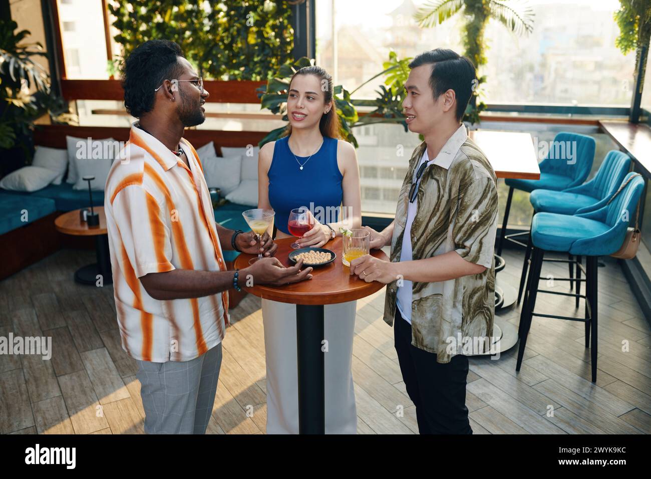 Young people having snacks, drinking and talking at party Stock Photo ...
