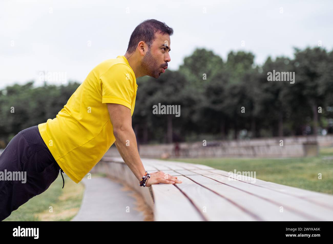 athlete man builds arm muscles with bench push-ups in park, preparing ...