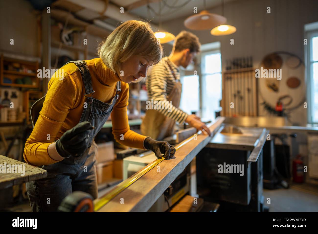 Carpentry workshop, craftsmen working together. Girl, guy measure ...