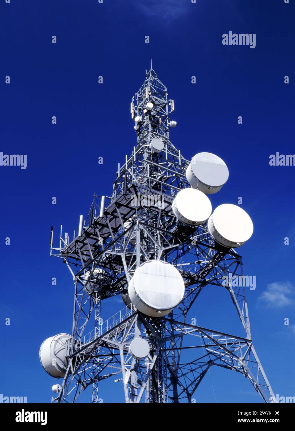 Roadside communications mast with telecoms installations against blue ...