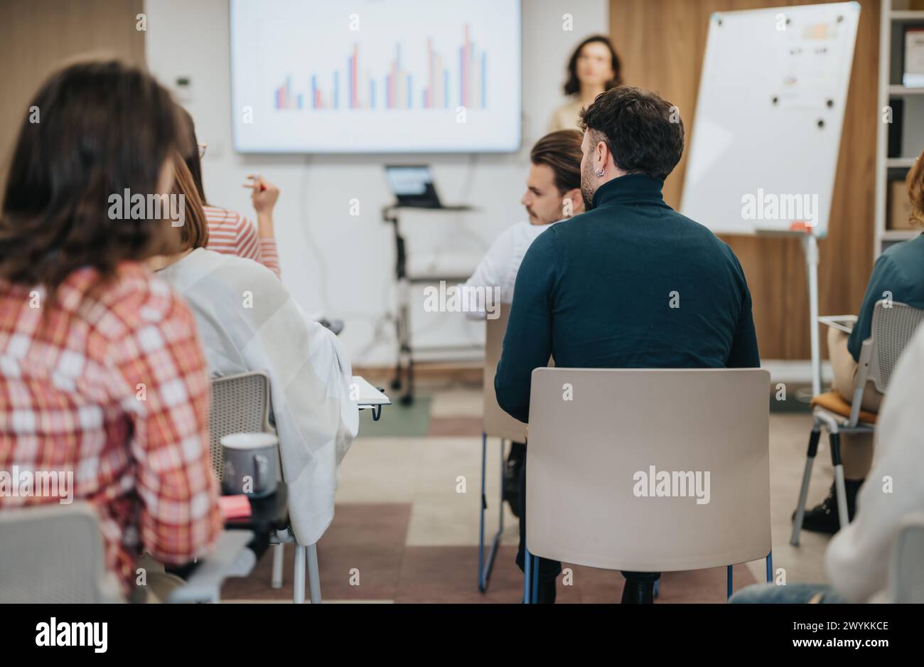 Focused professionals watching a presenter explaining a bar chart in a ...