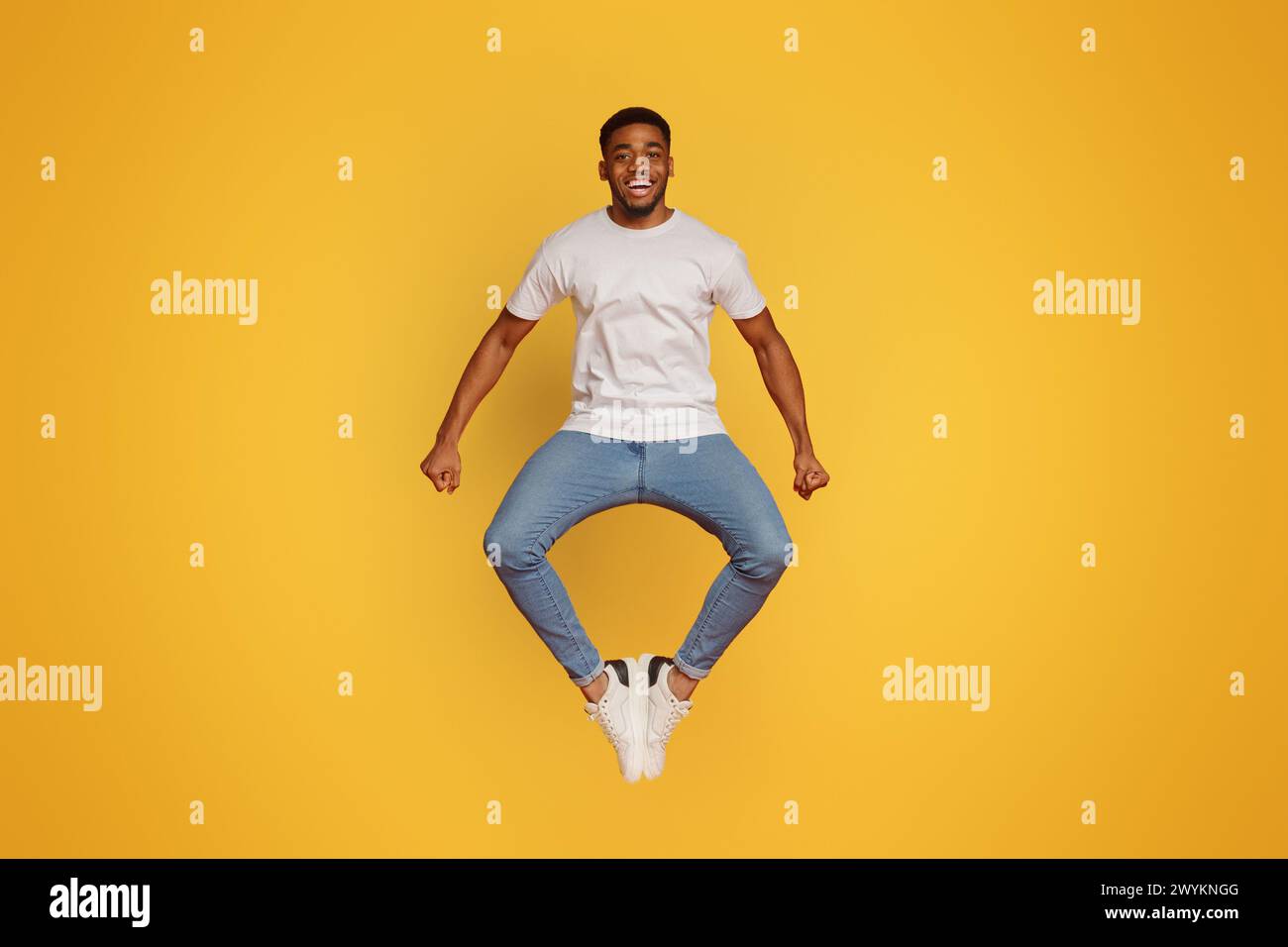 Positive african american guy jumping and clapping his legs Stock Photo ...