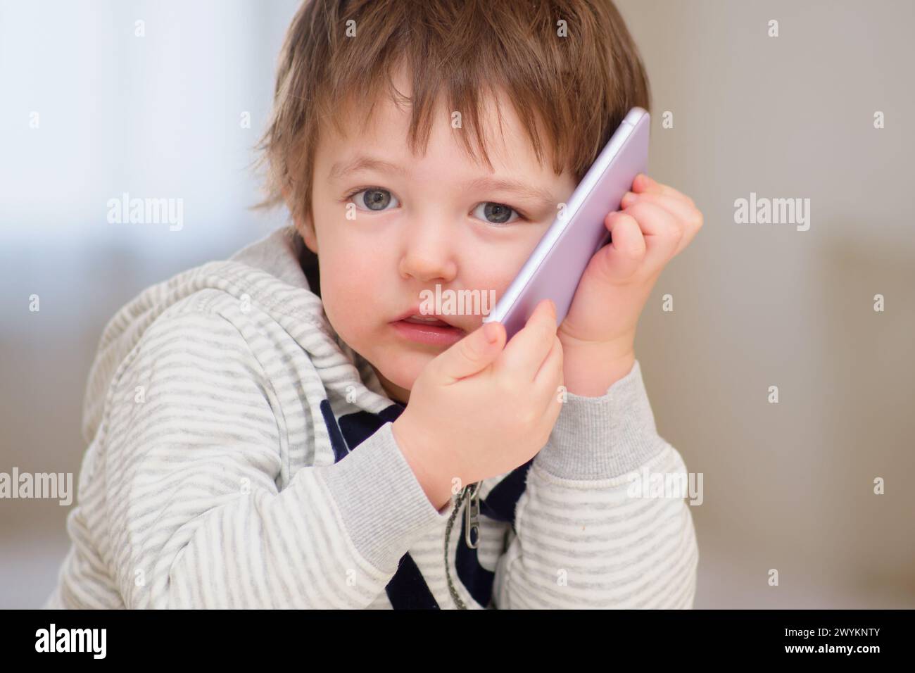 A scared baby is talking on a mobile phone. A sad child is on the phone ...