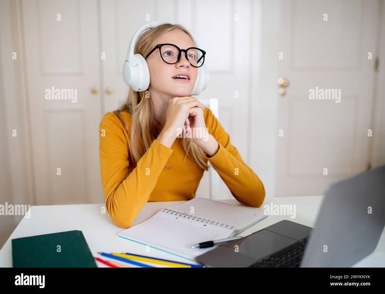 Thoughtful Teen Girl in Orange Shirt Listening Intently With Headphones ...