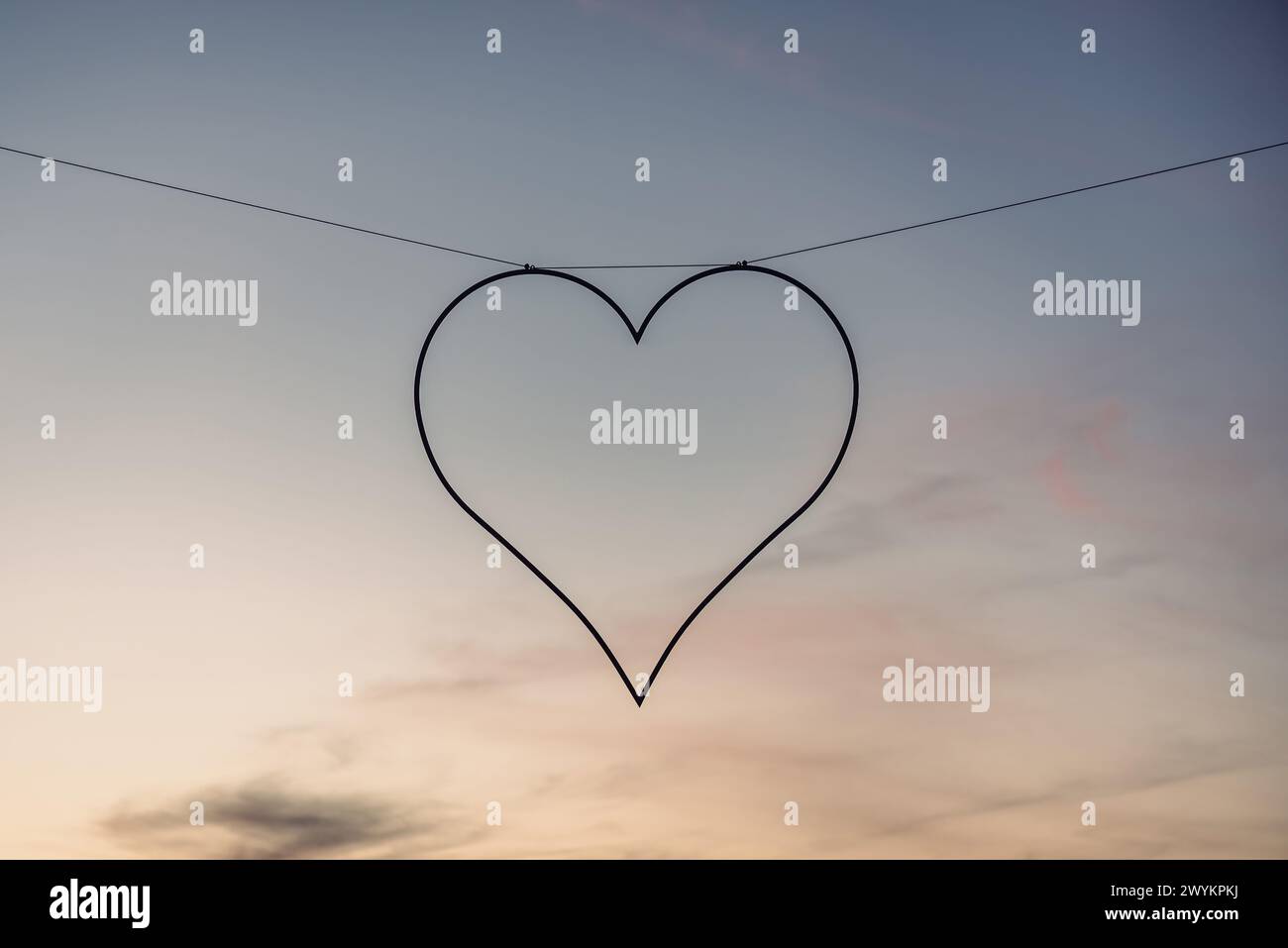 A delicate heart-shaped silhouette dangles from a thin wire, suspended ...