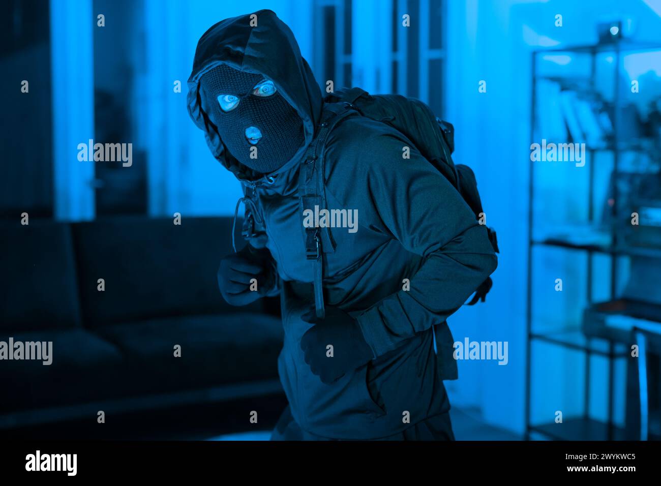 Masked man burglar ducking and hiding indoors Stock Photo - Alamy