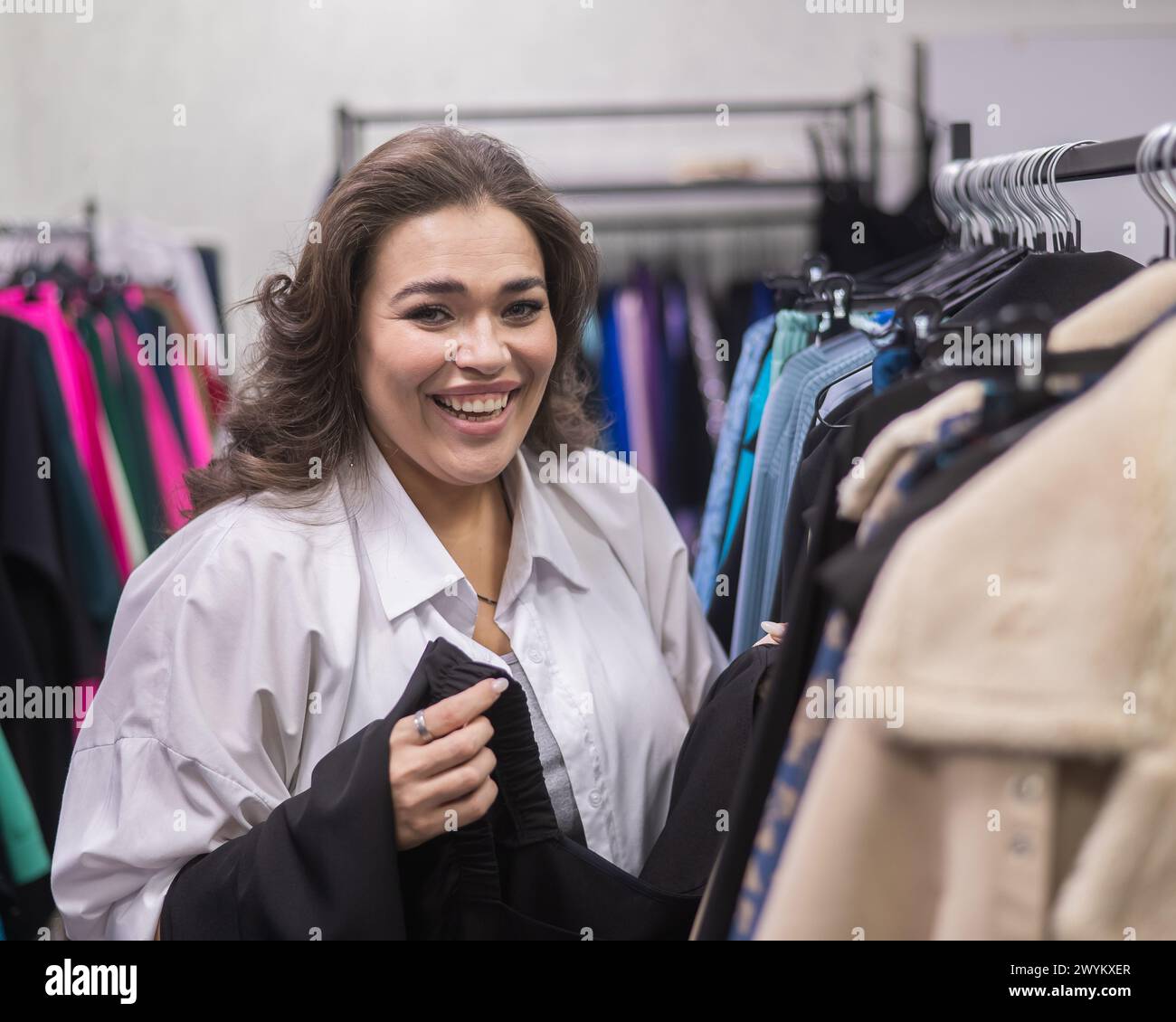 Portrait of a smiling fat woman choosing clothes in a plus size store ...