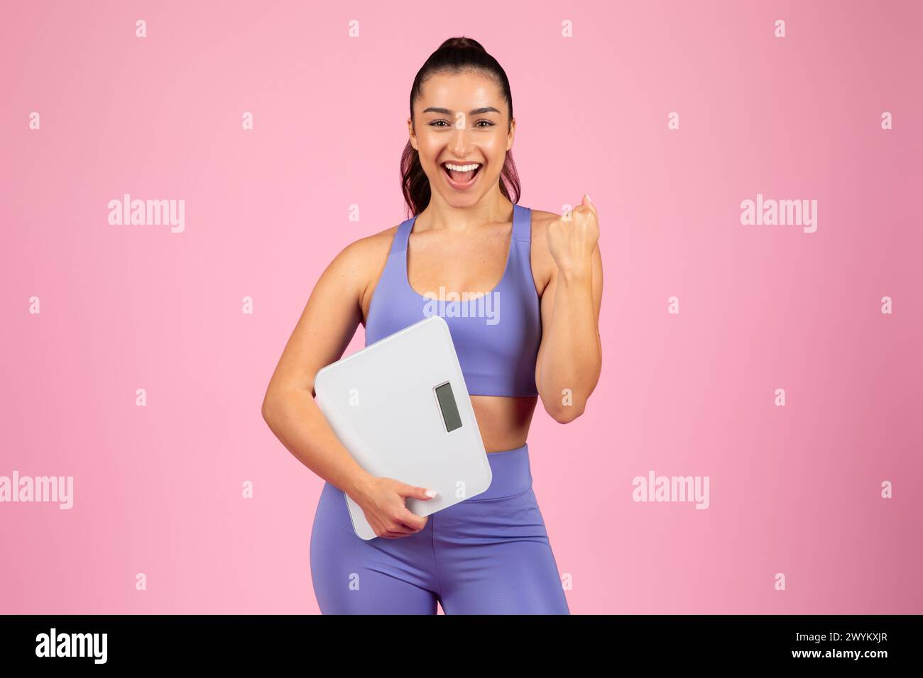 Excited woman with scale celebrating Stock Photo - Alamy