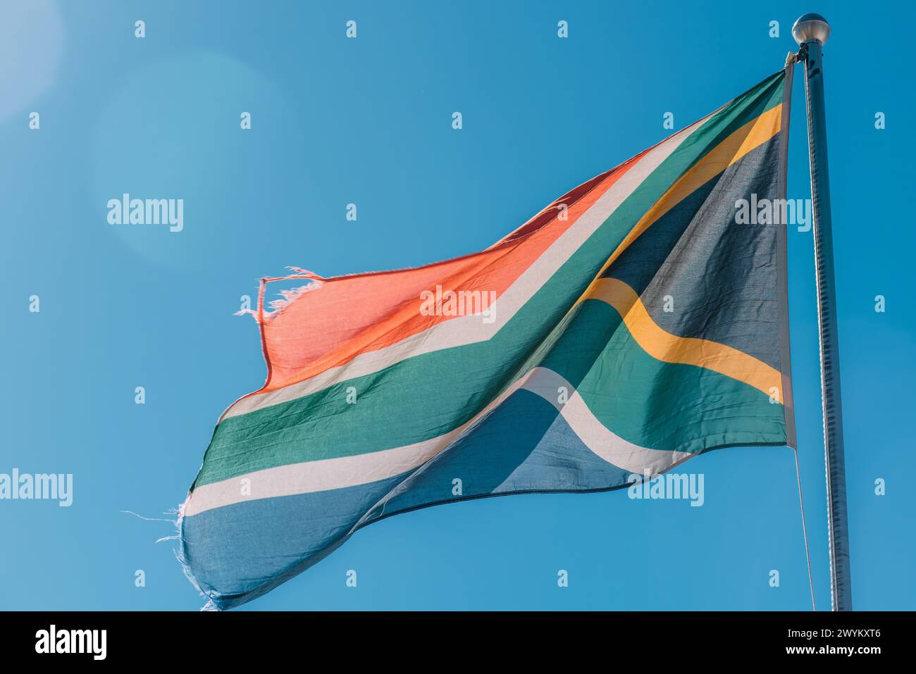 The South African flag, frayed at the edges, is caught mid-flutter ...