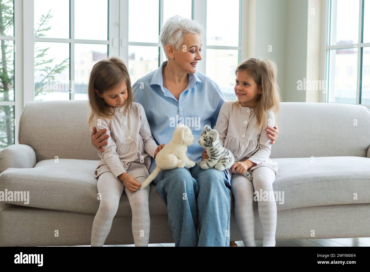 Happy family at home. Two little girls sisters twins grandmother ...