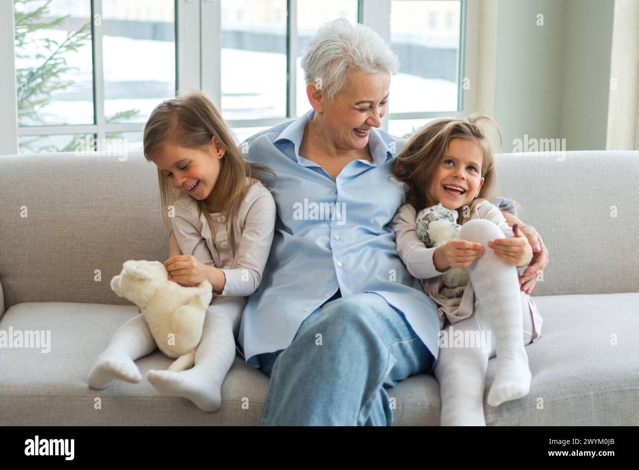 Happy family at home. Two little girls sisters twins grandmother ...