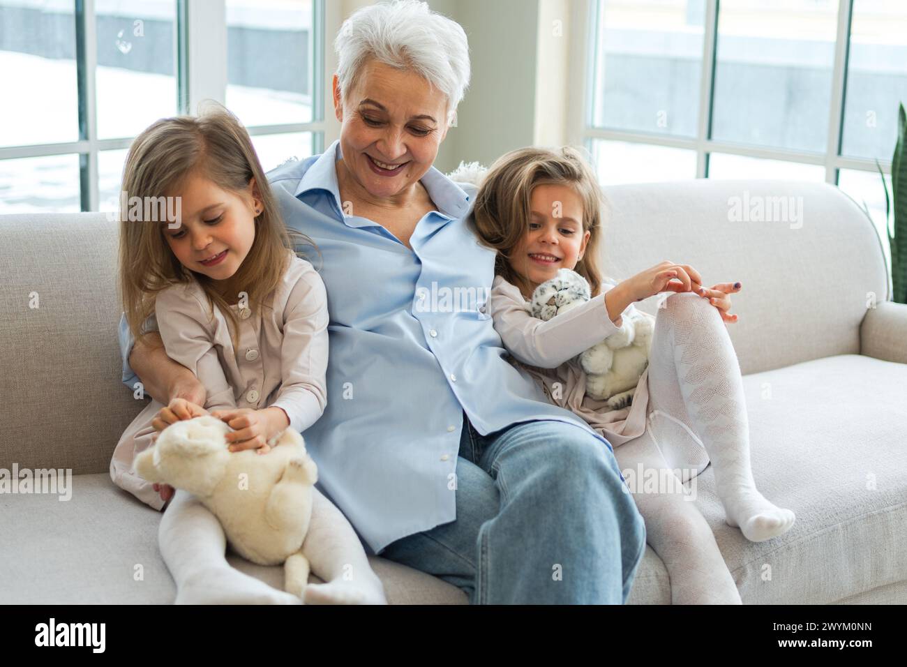 Happy family at home. Two little girls sisters twins grandmother ...