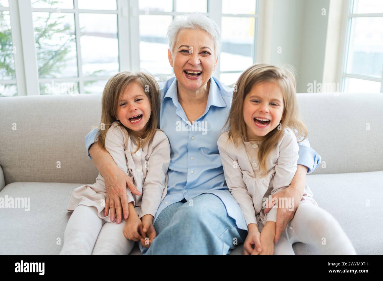 Happy family at home. Two little girls sisters twins grandmother ...