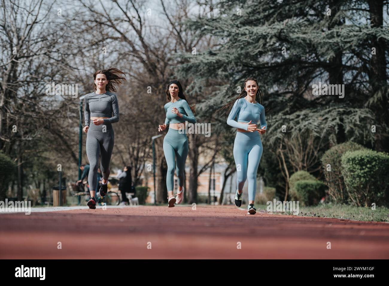 Three women running together on park track enjoying fitness and healthy ...