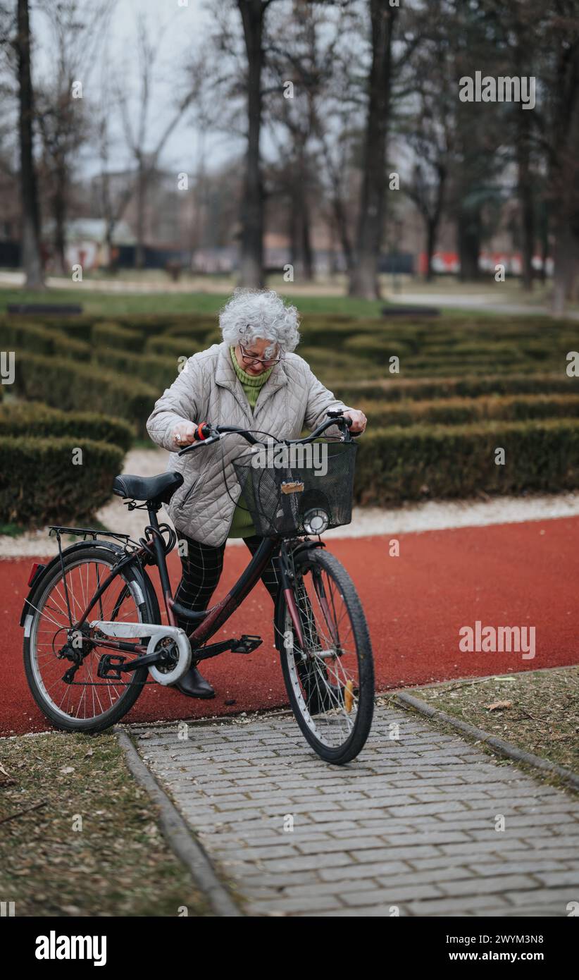 Active senior woman enjoying a bike ride in the park, promoting healthy ...