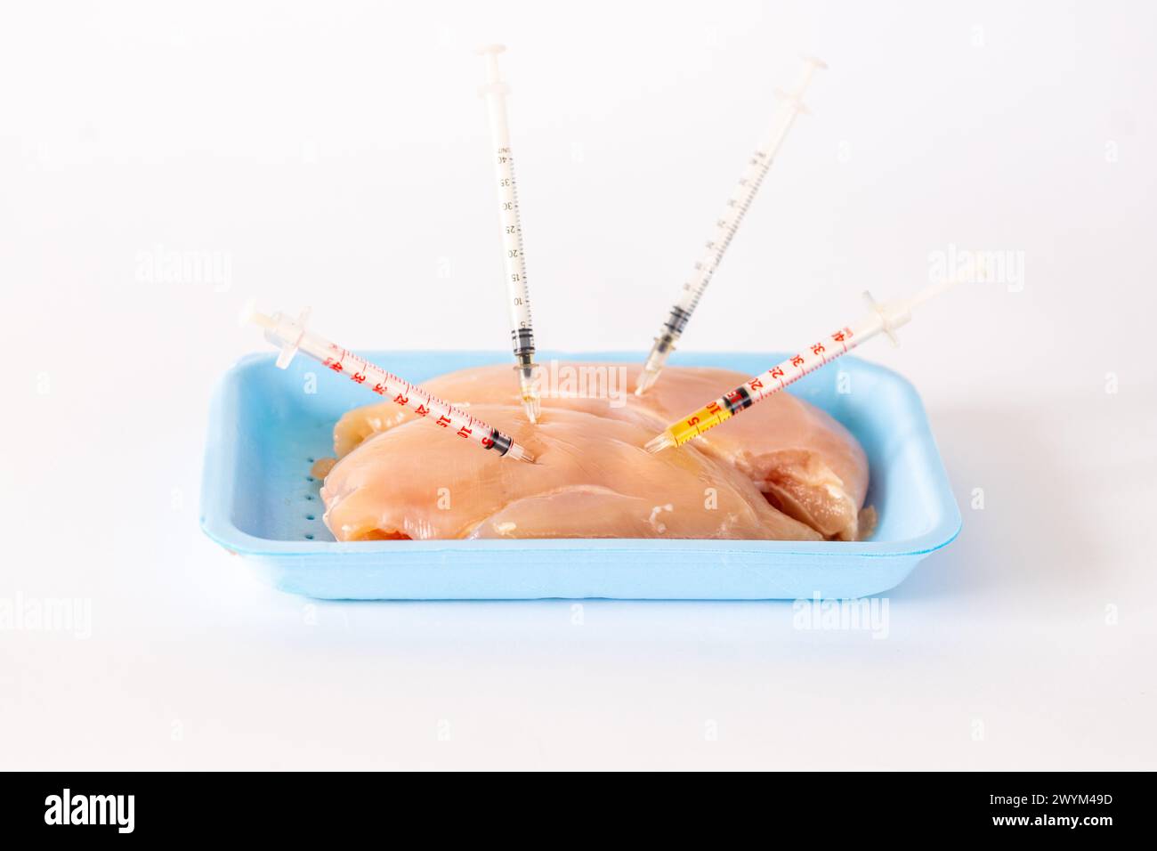 Chicken meat on a tray with syringes stuck in it, Nutrition concept ...