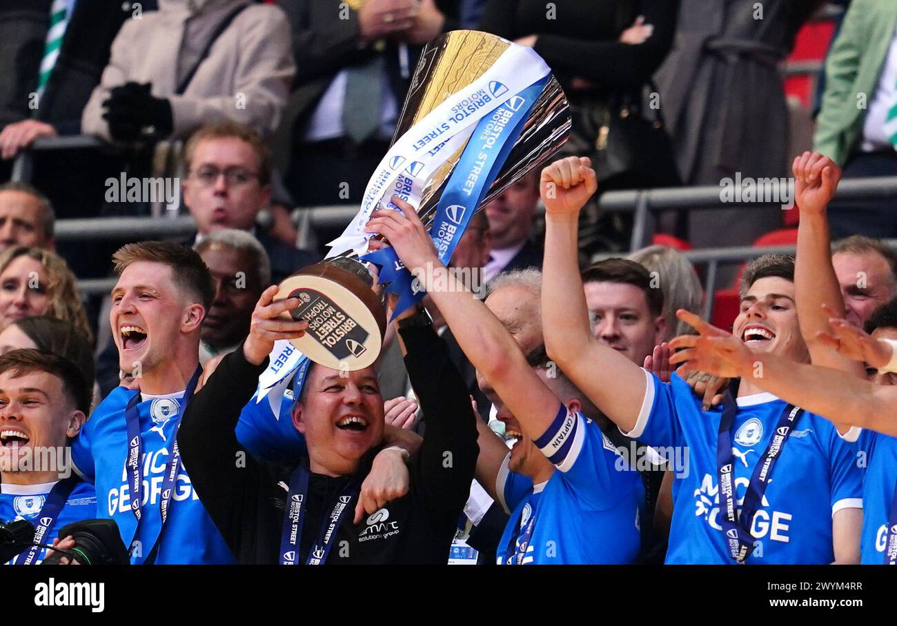 Peterborough United's Harrison Burrows and manager Darren Ferguson lift ...