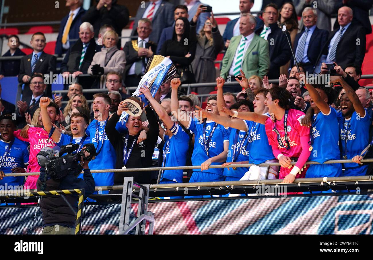 Peterborough United's Harrison Burrows and manager Darren Ferguson lift ...