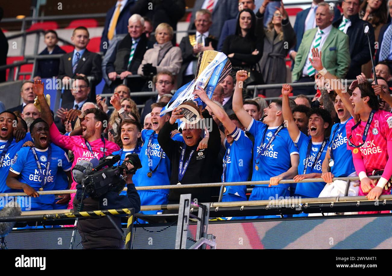 Peterborough United's Harrison Burrows and manager Darren Ferguson lift ...