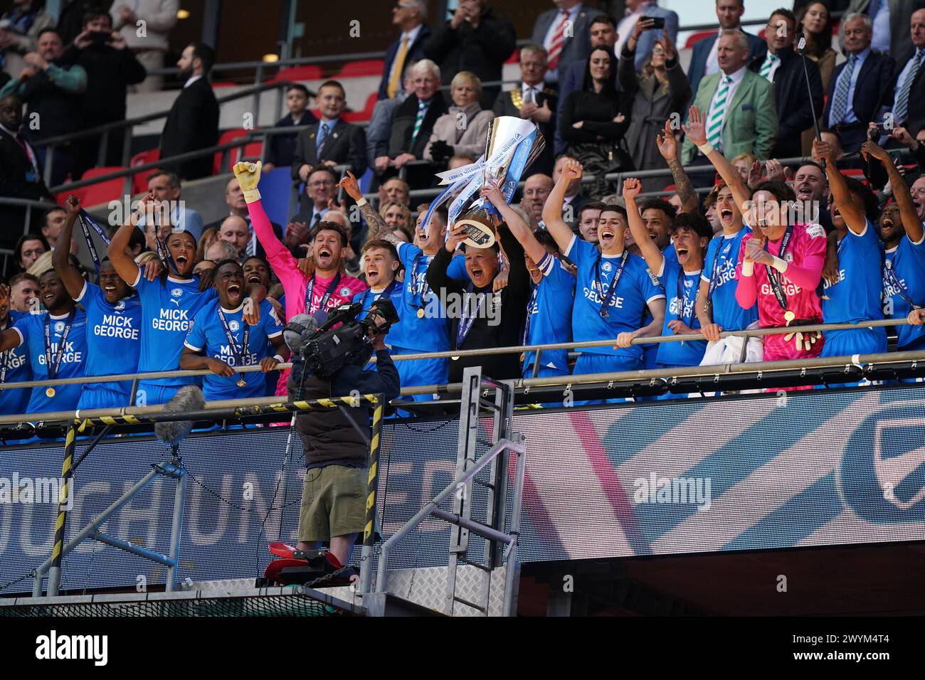 Peterborough United's Harrison Burrows and manager Darren Ferguson lift ...