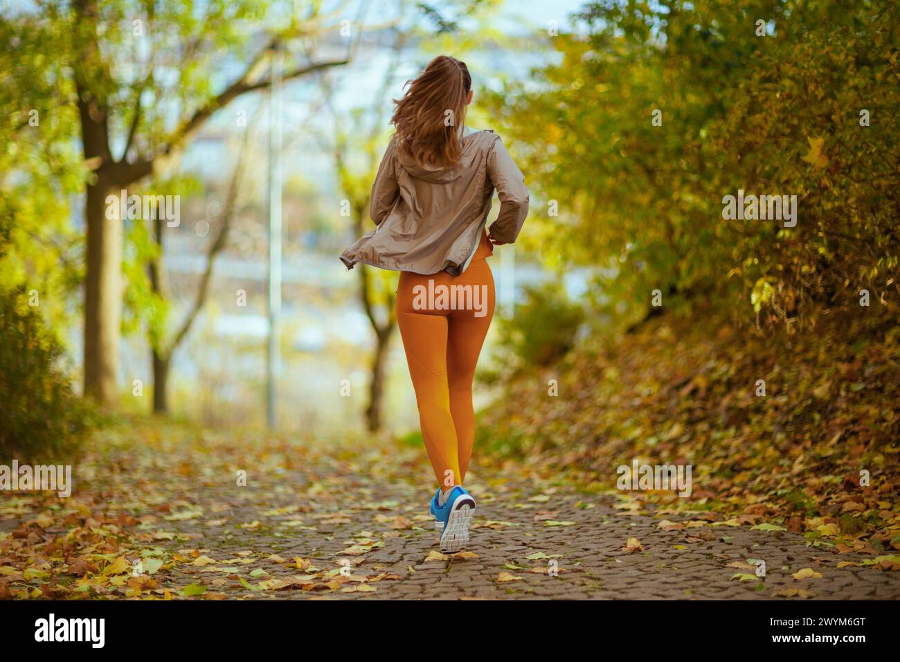Hello autumn. Seen from behind modern woman in fitness clothes in the ...