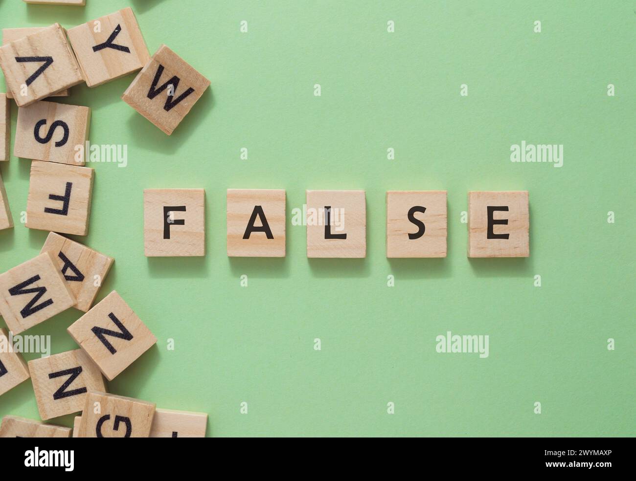 A jumble of wooden letters spell out the word false. The letters are ...