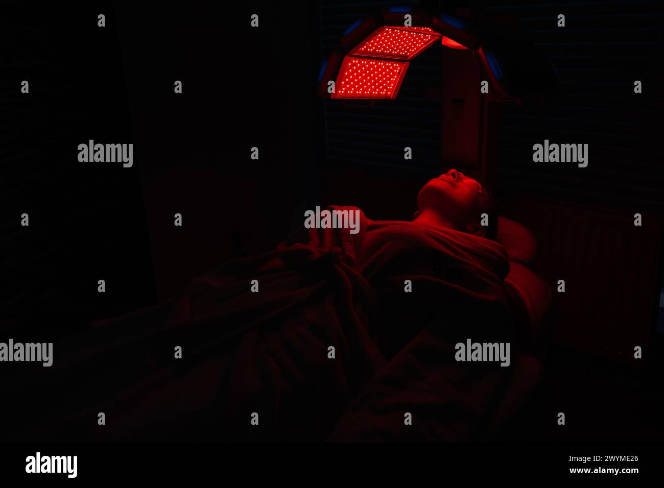 Remote view of female client in protective glasses having red LED light ...