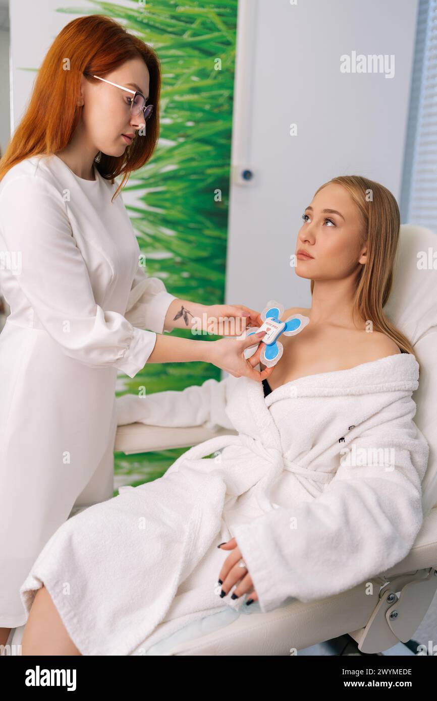 Vertical side view of skilled female cardiologist attaching holter ...