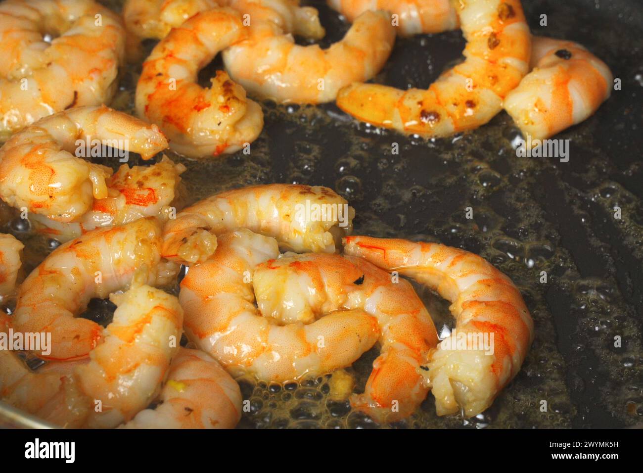 Shrimp being cooked in a hot frying pan with sizzling oil, showcasing ...
